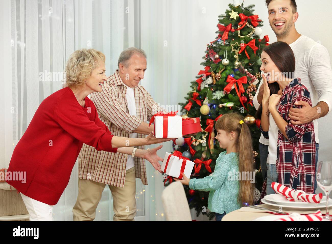 Happy members of family giving Christmas presents to each other Stock ...