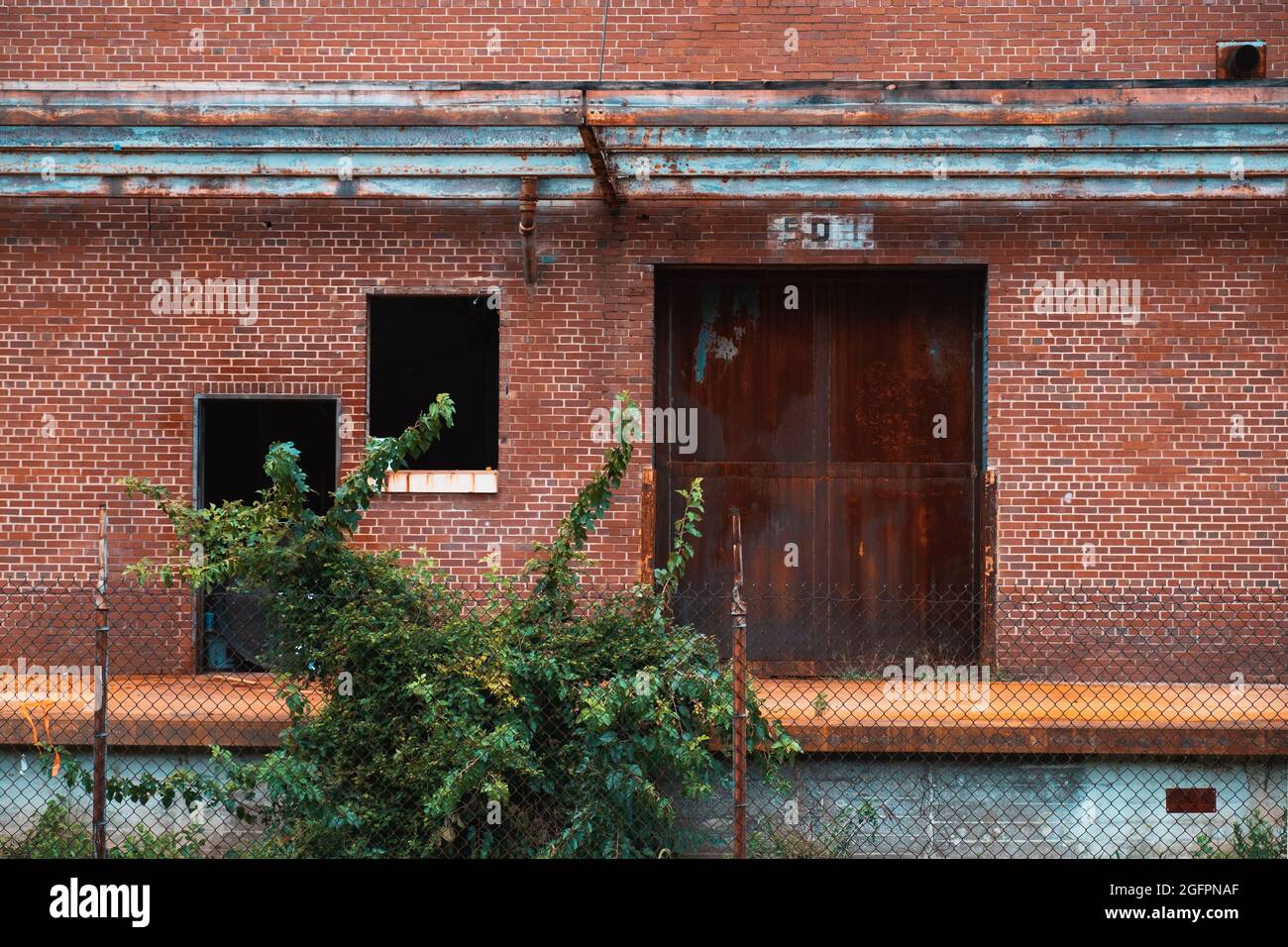 Rusted factory doors set in brick wall on abandoned loading dock with ...
