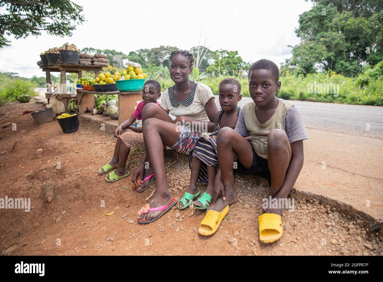 Group of African siblings sitting on the side of the road, they are ...