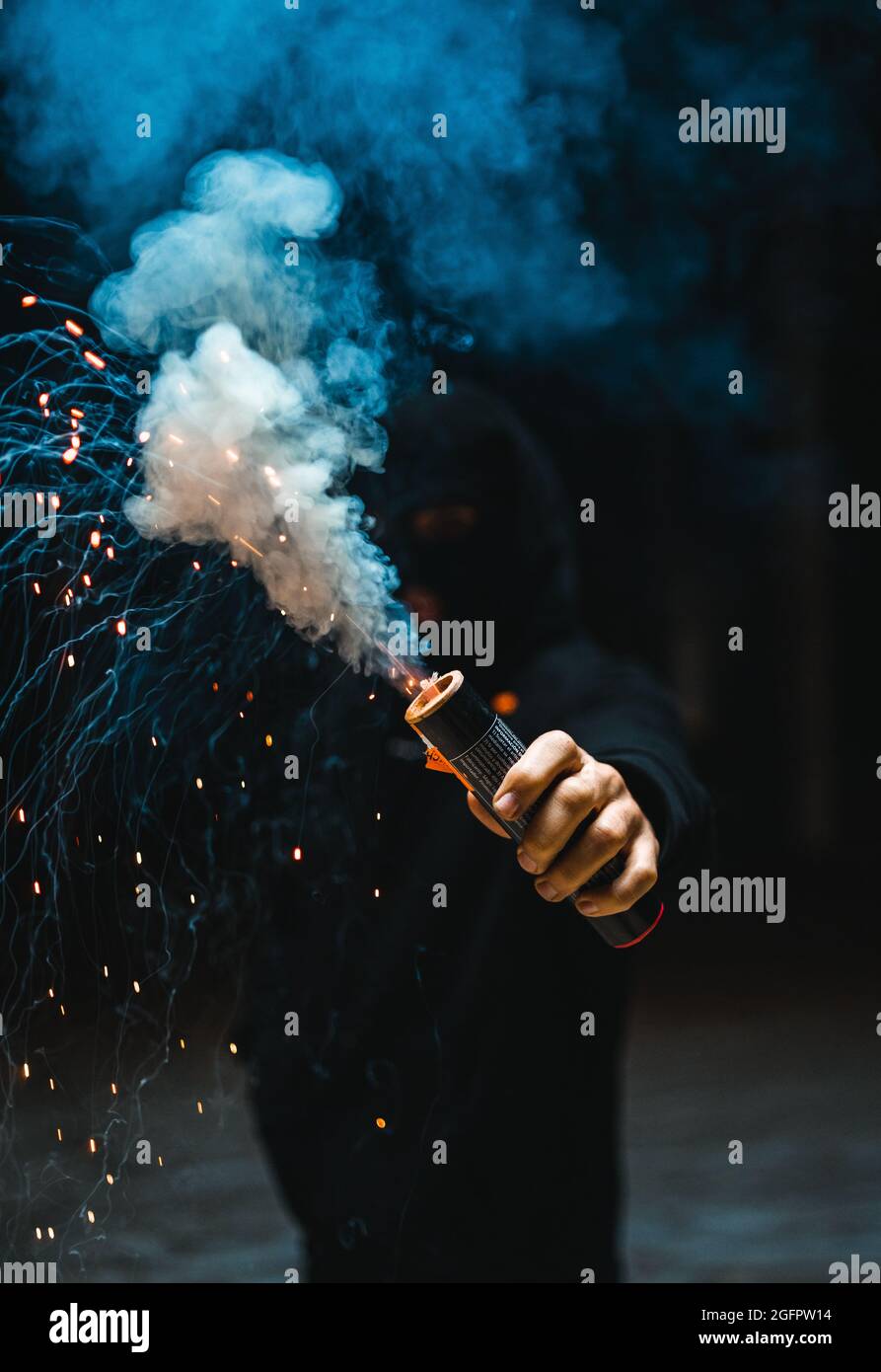 View of a man holding an explosive in his hands and smoke coming out of ...
