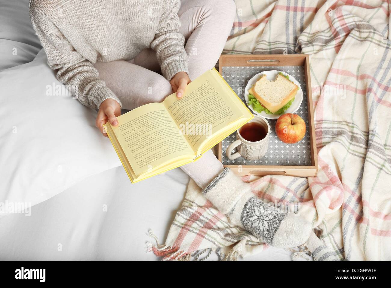 Girl with food reading book on bed Stock Photo - Alamy