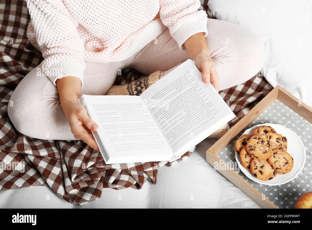 Girl with food reading book on bed Stock Photo - Alamy