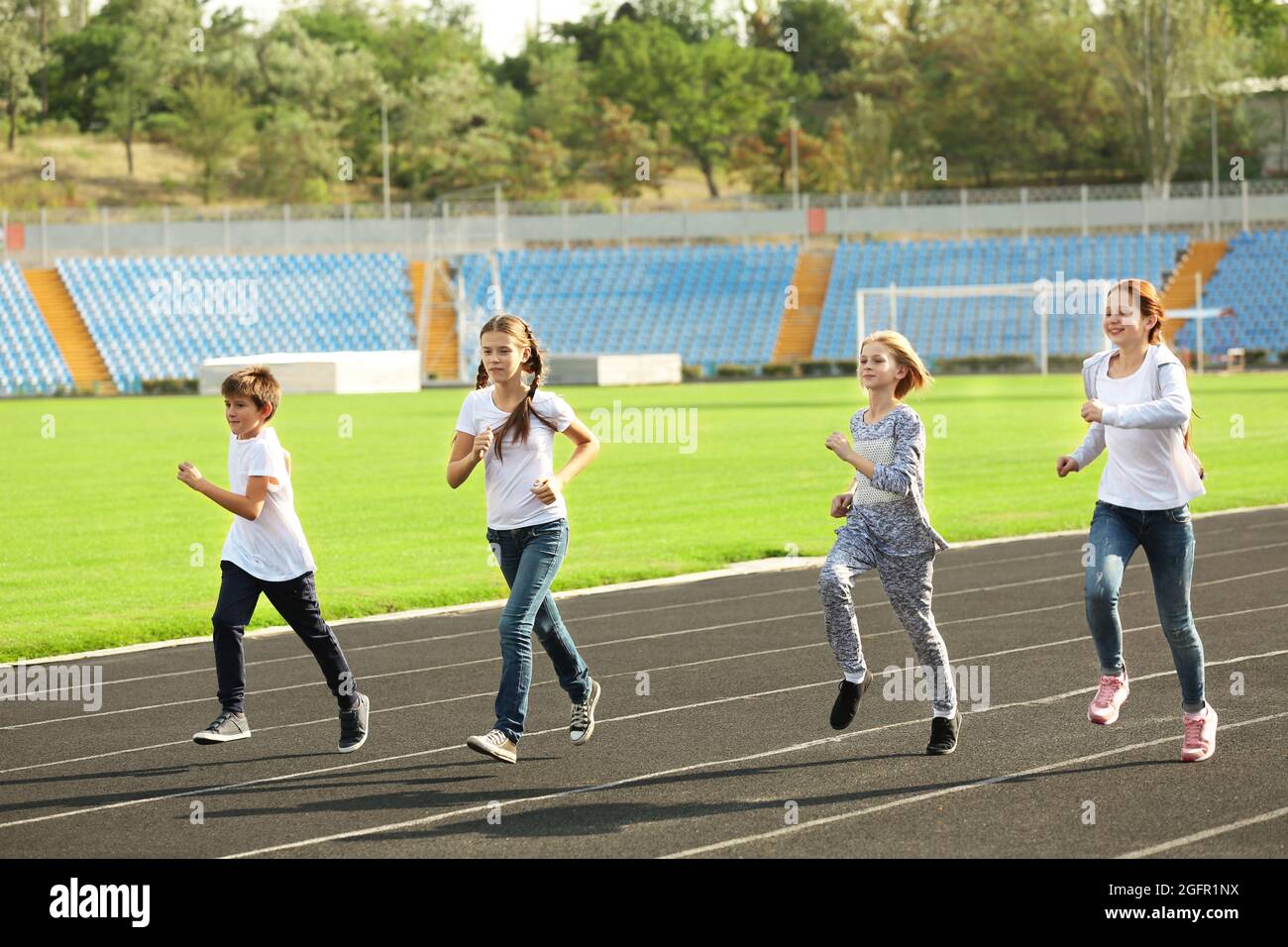 Sporty children running on track at stadium Stock Photo - Alamy