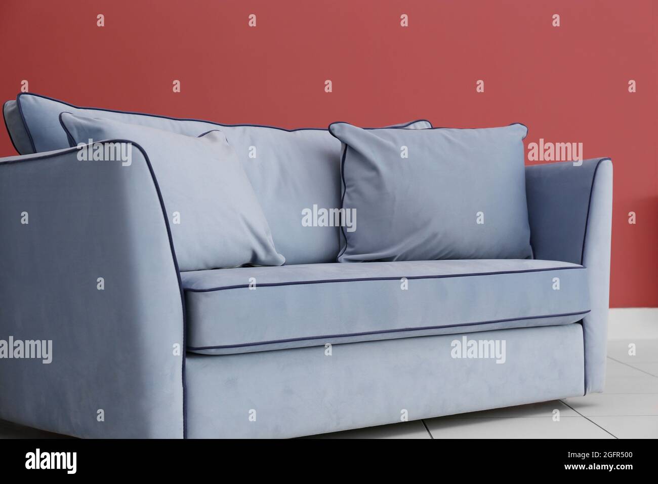 Modern couch on red wall background Stock Photo - Alamy
