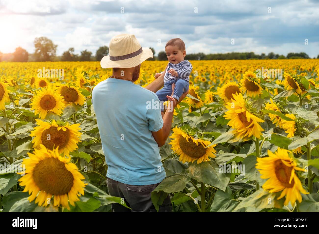 Portrait of a Caucasian father and his baby having fun in a field of ...