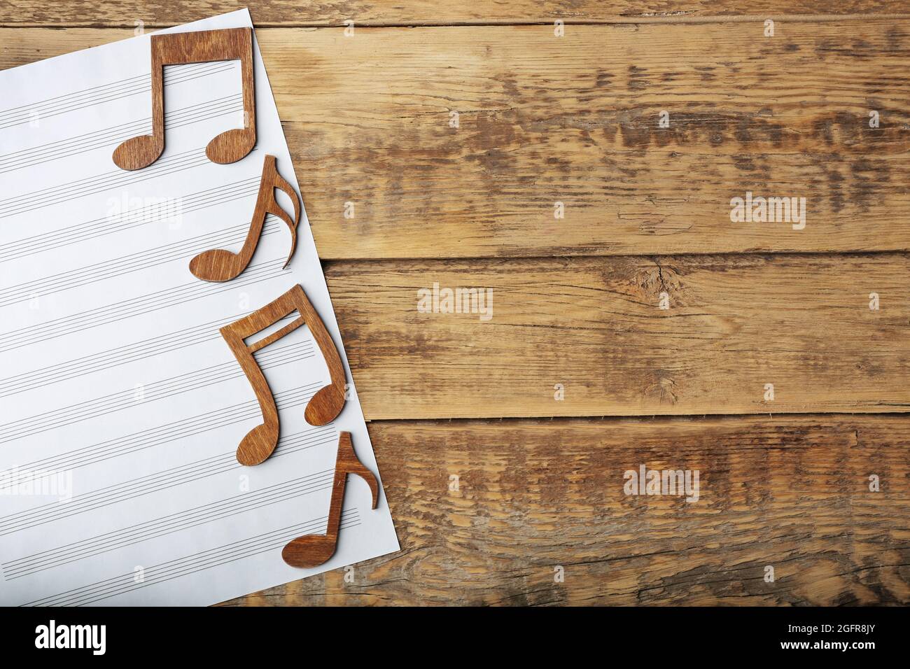 Music notes and sheet of paper on wooden background Stock Photo - Alamy