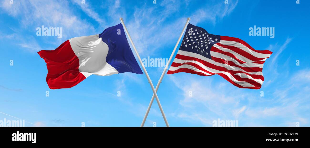 flags of USA and France waving in the wind on flagpoles against the sky ...