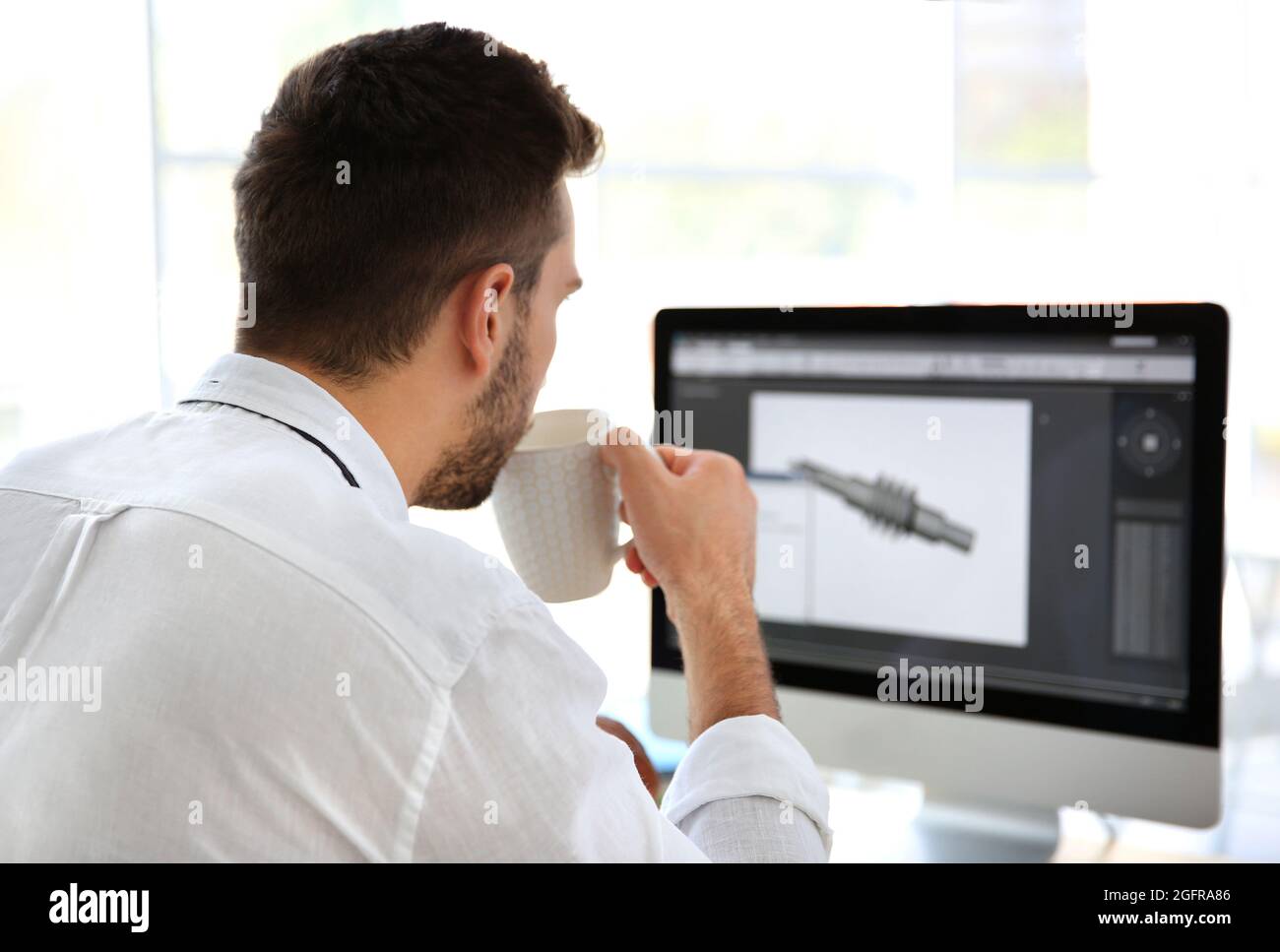 Young man drinking coffee while working with computer in office, close ...