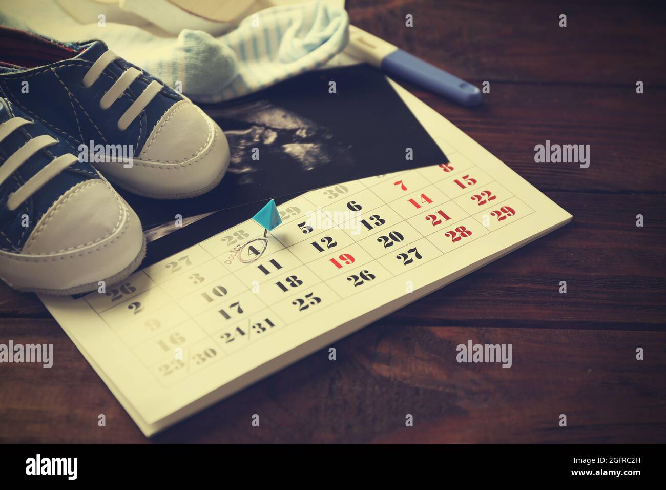 Calendar with ultrasound scan of baby and children shoes, closeup Stock ...