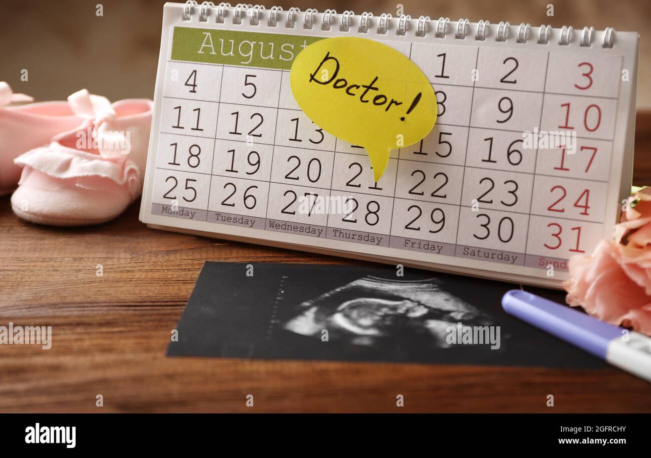 Calendar with ultrasound scan of baby on wooden background Stock Photo ...