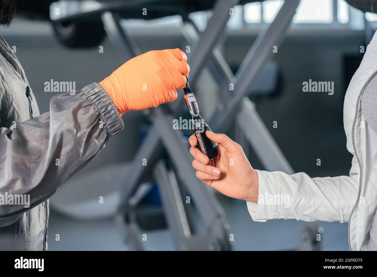 Auto Mechanic giving the car keys to his female customer in workshop at ...