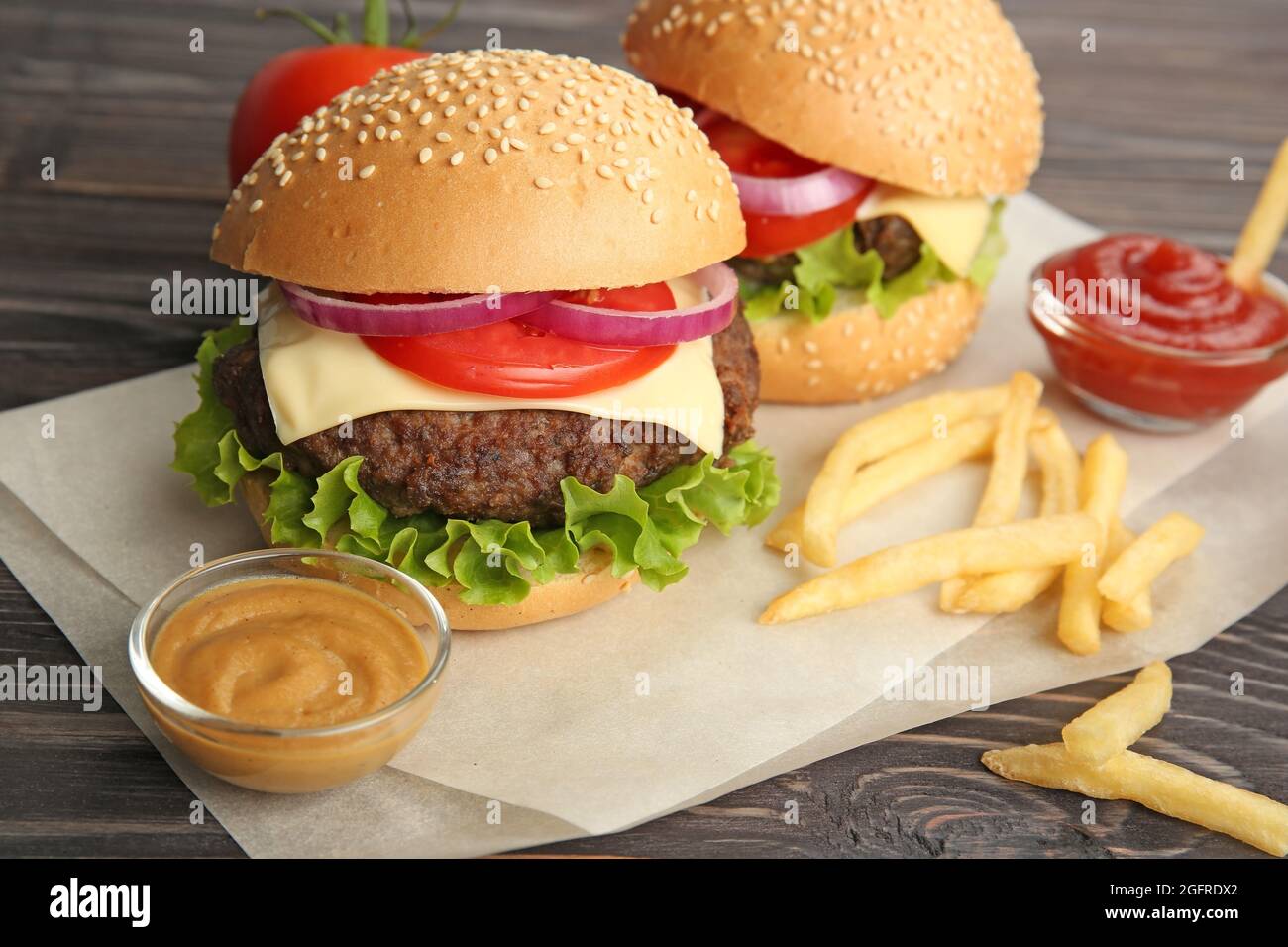 Delicious cheeseburgers with french fries on parchment closeup Stock ...