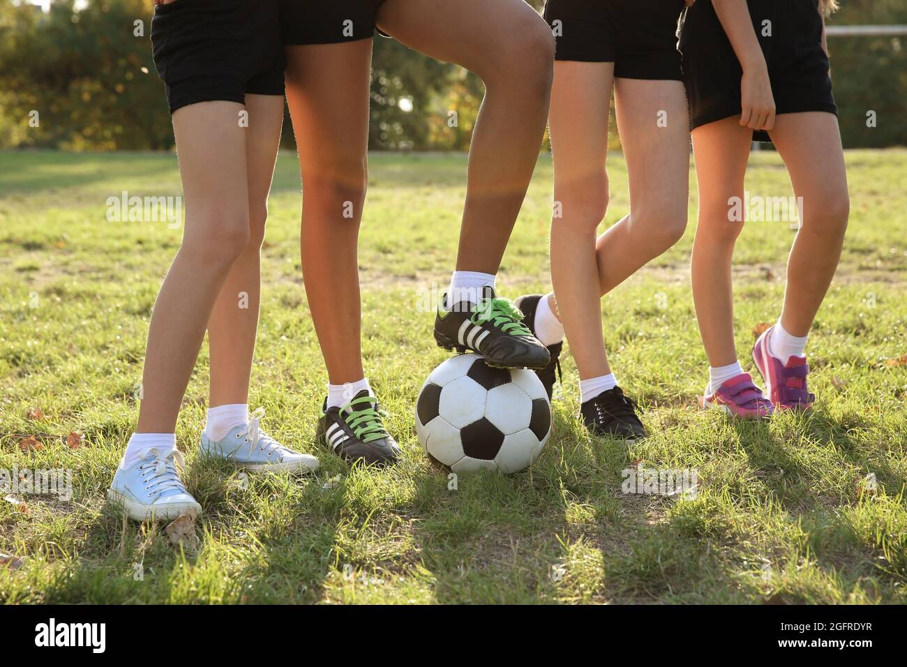 Kids legs with football ball on field Stock Photo - Alamy