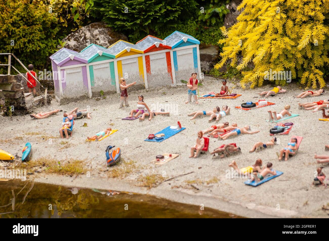 Closeup of tiny model people sitting on a sandy beach Stock Photo - Alamy