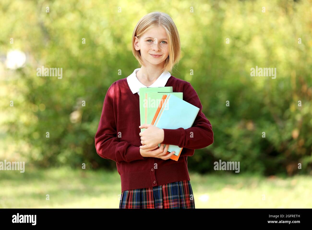 Schoolgirl with books outdoors on blurred background Stock Photo - Alamy