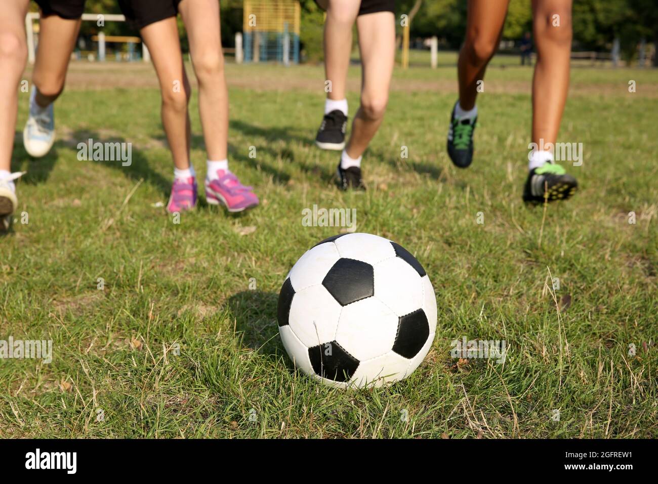 Kids legs with football ball on field Stock Photo - Alamy
