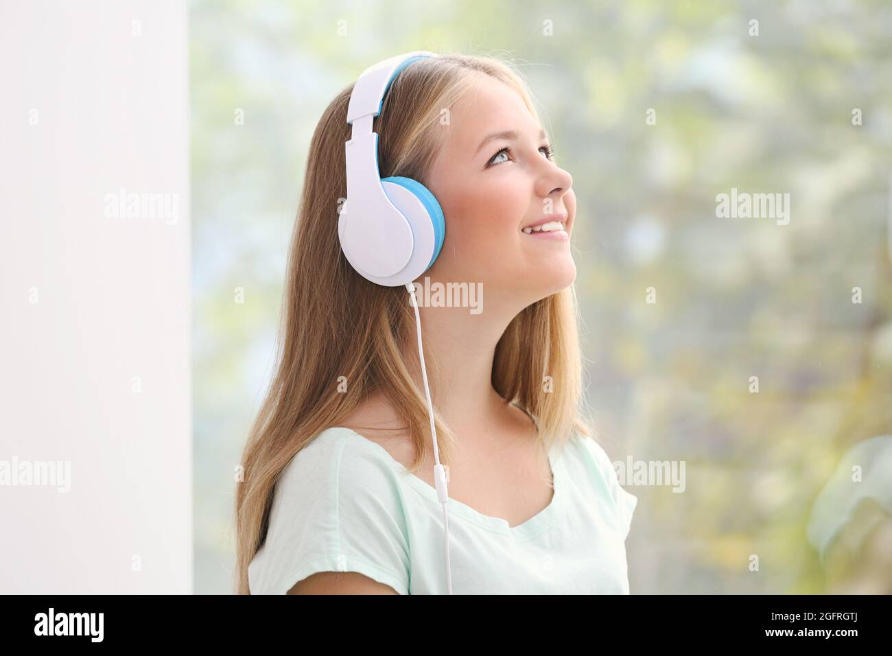 Cute teenager listening music on window background Stock Photo - Alamy