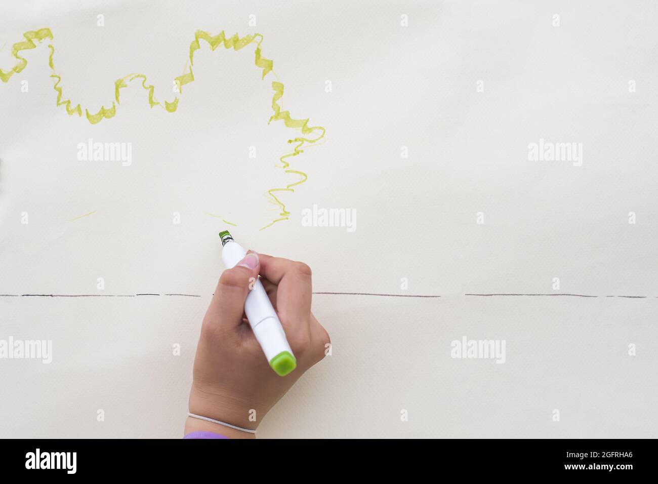 Female hand draws wavy lines on paper with green marker. A sketch of ...
