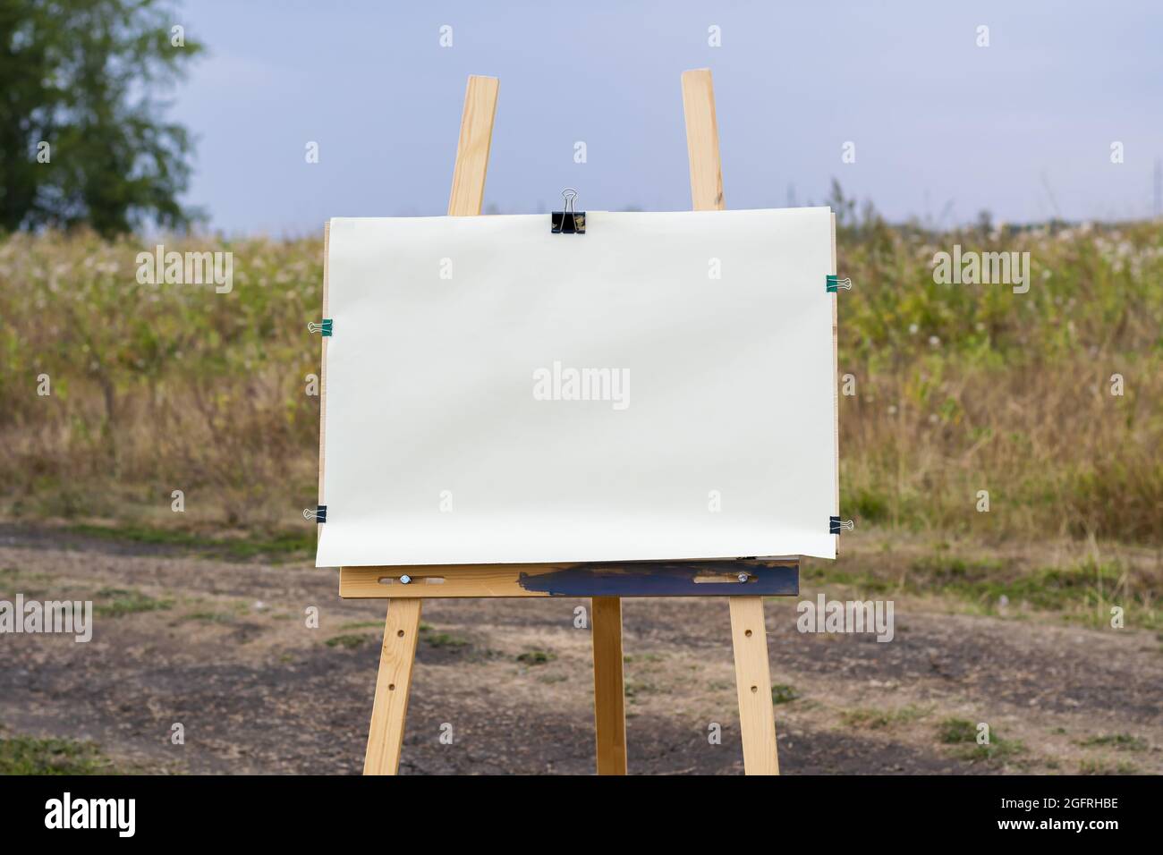 An artistic easel with a blank sheet of drawing paper stands against ...