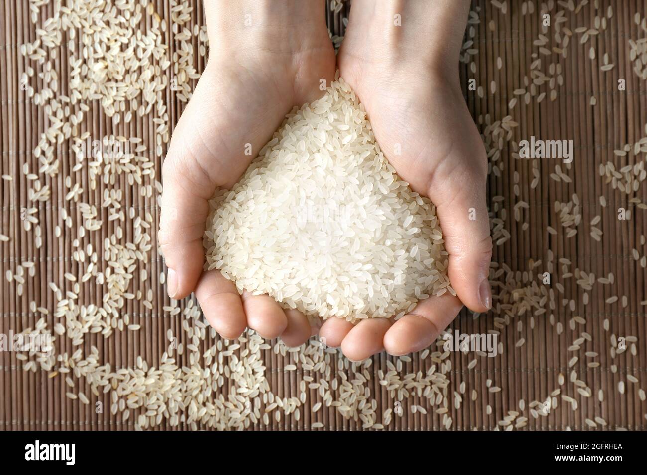 Female hands full of parboiled rice on bamboo mat background Stock ...