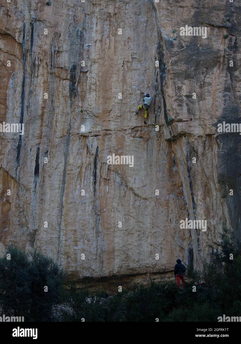 Person climbing the high cliff while another watches them from the ...