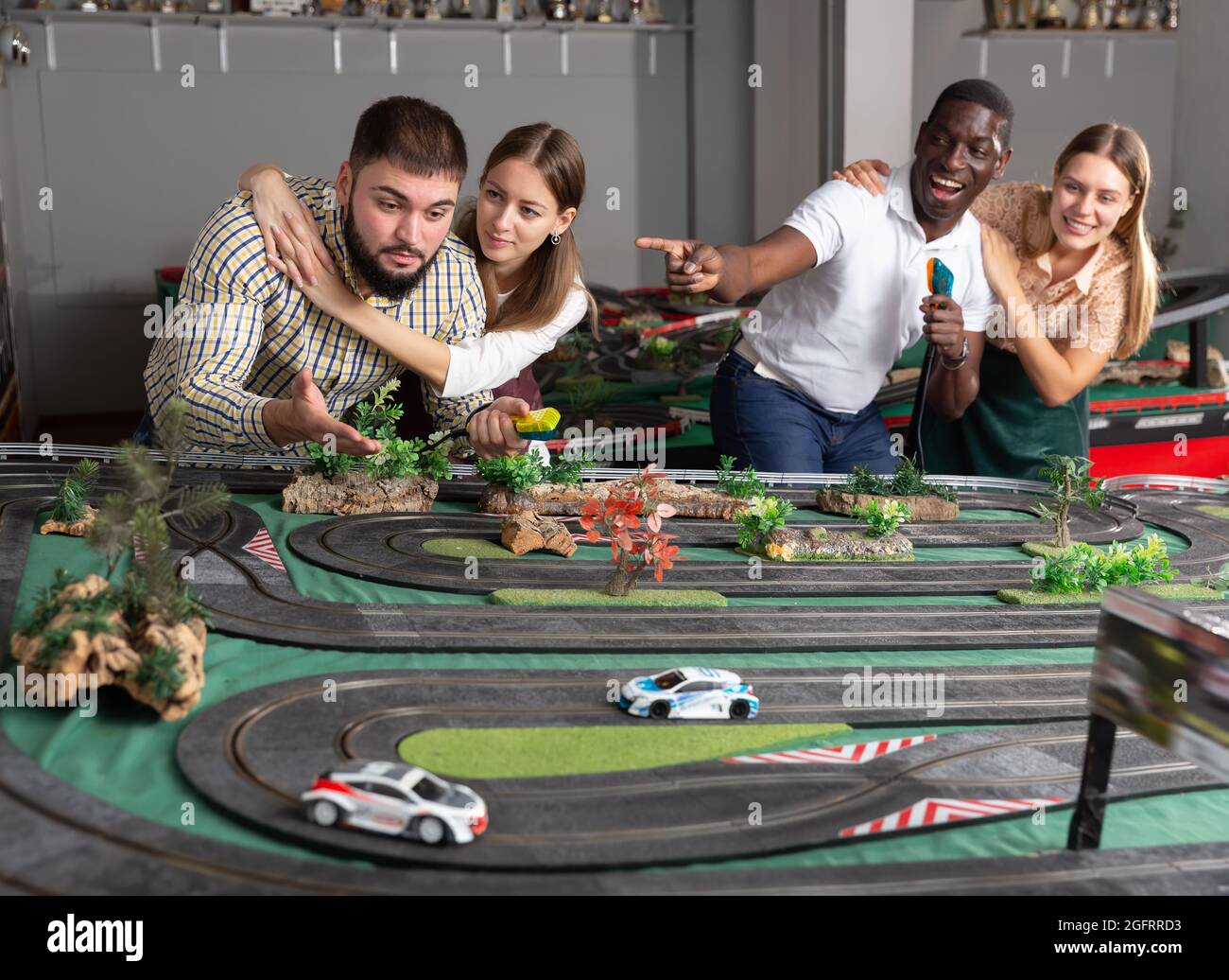 Two teams from couples play slot car racing game Stock Photo - Alamy