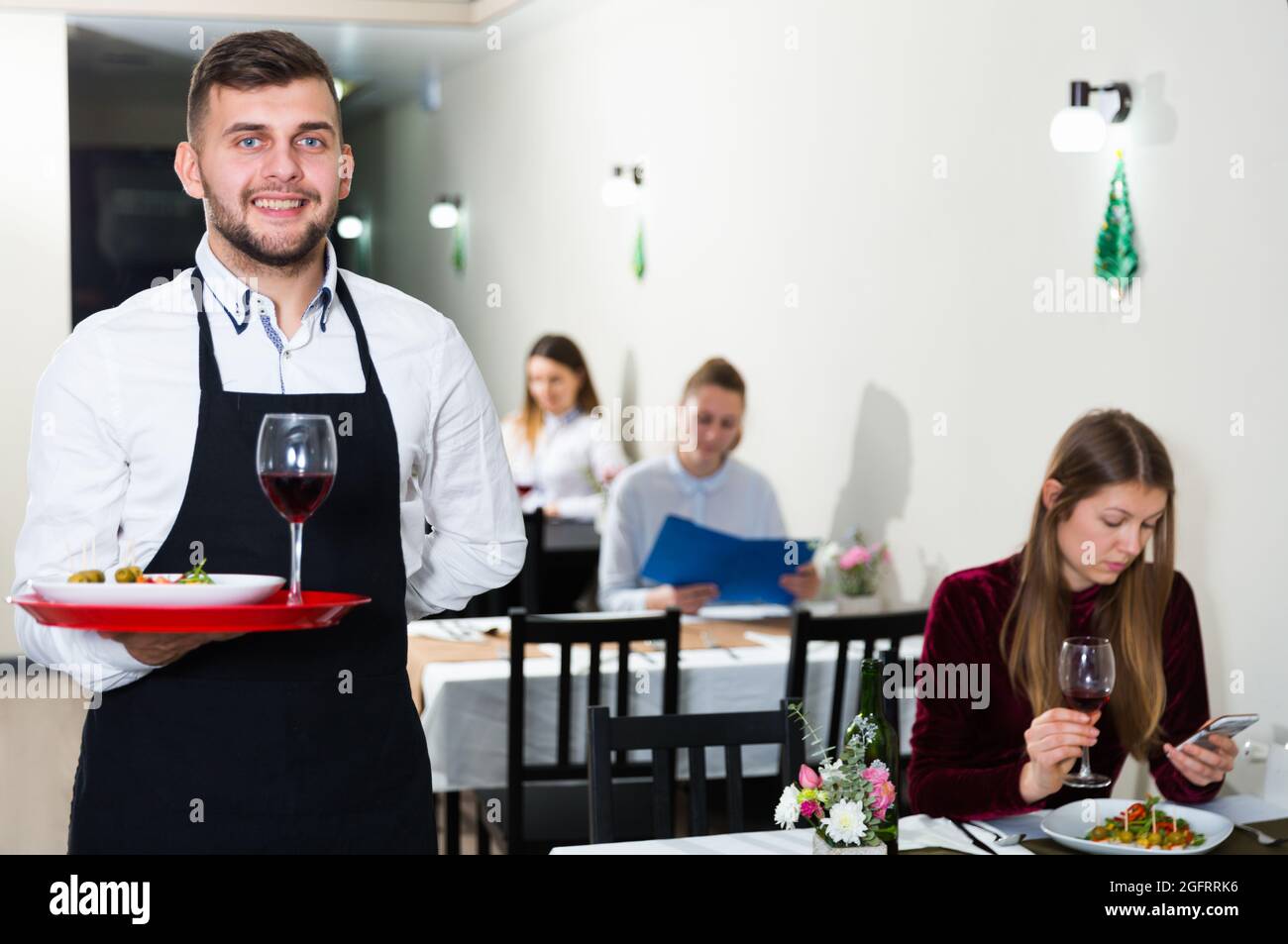 Affable male waiter is standing with order in luxury restaurante Stock ...