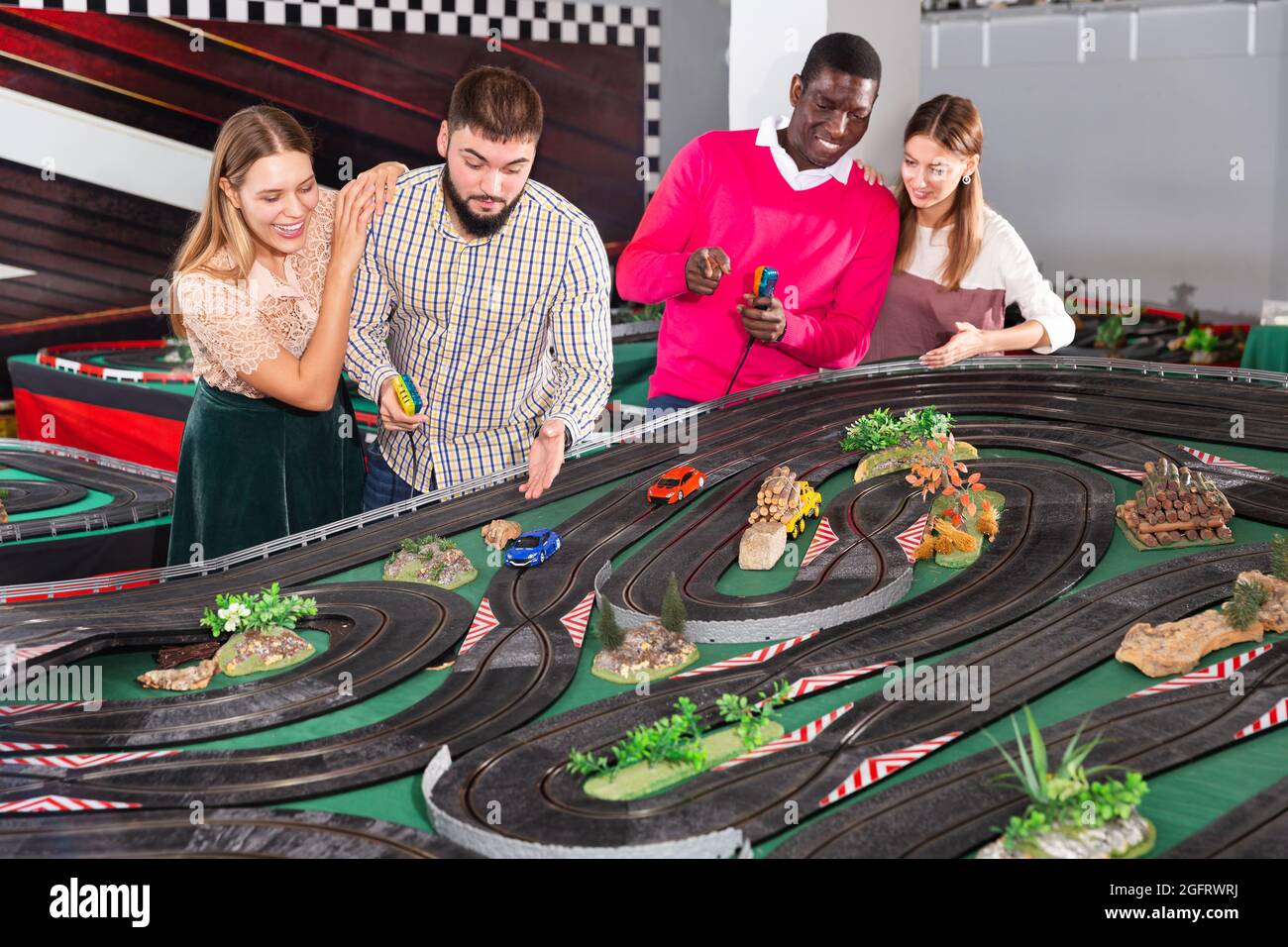 Girls with guys play slot car racing models Stock Photo - Alamy