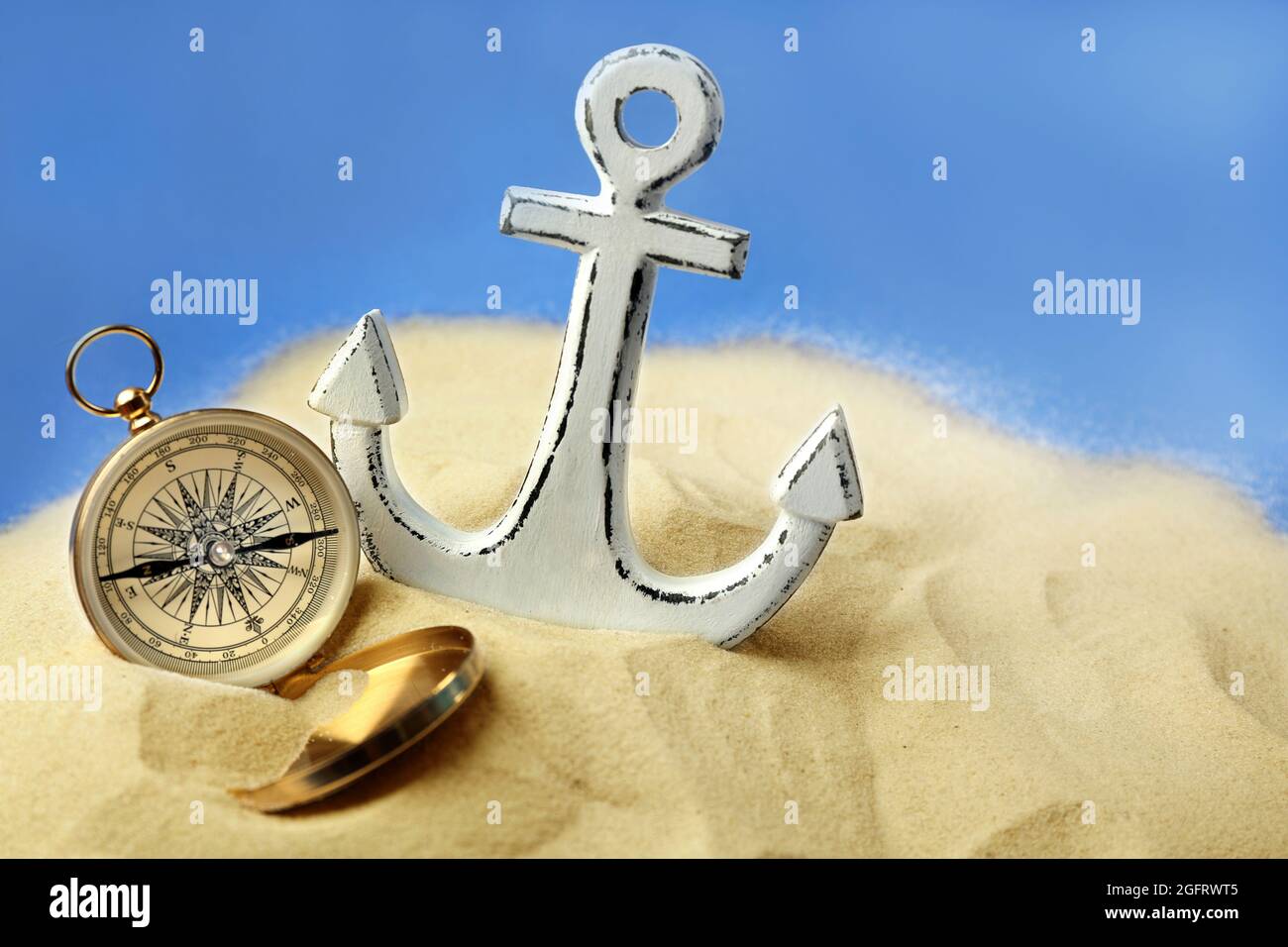 Anchor and compass in sand on blue background. Columbus Day concept ...