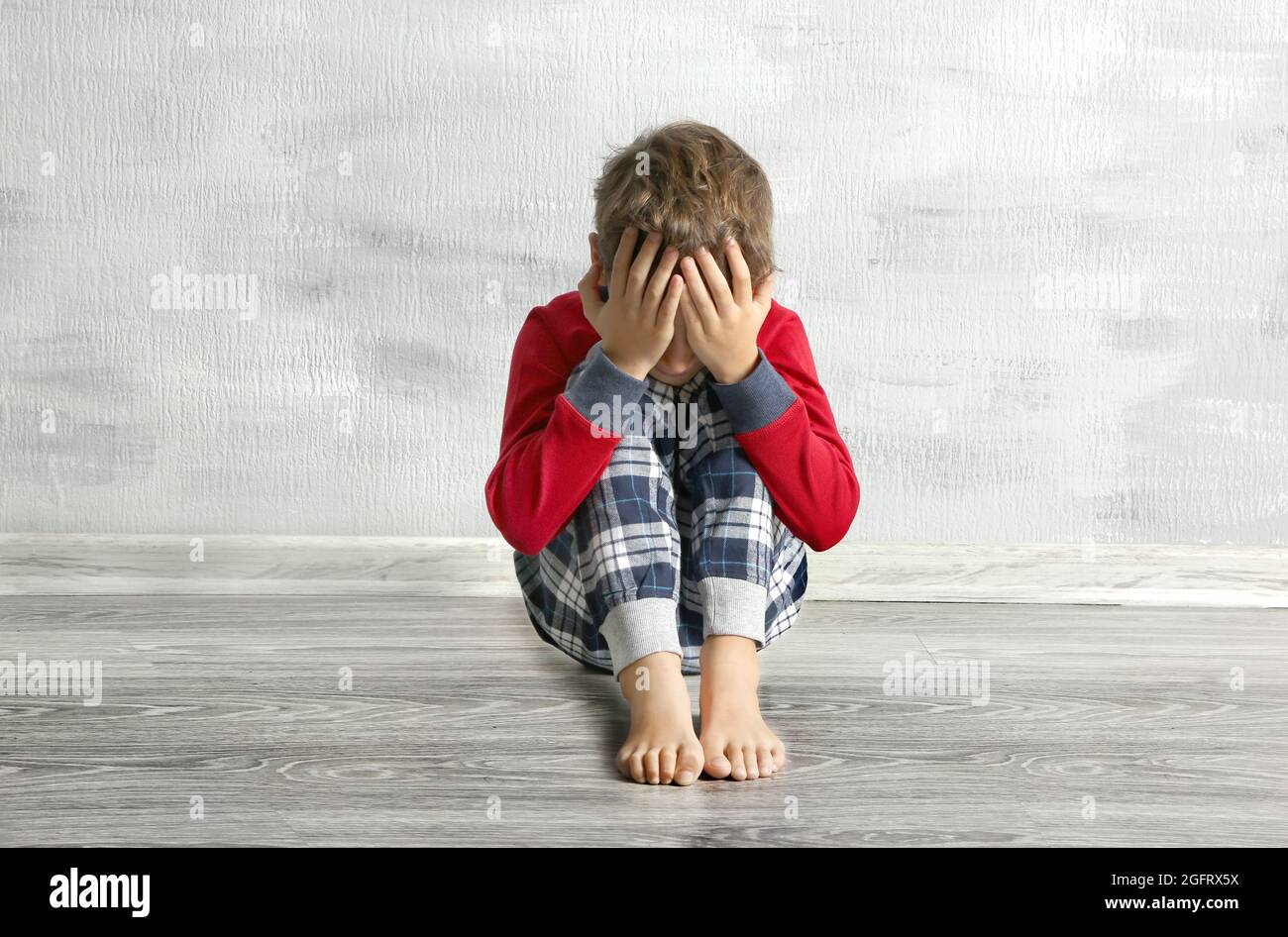 Crying little boy on floor in empty room Stock Photo - Alamy