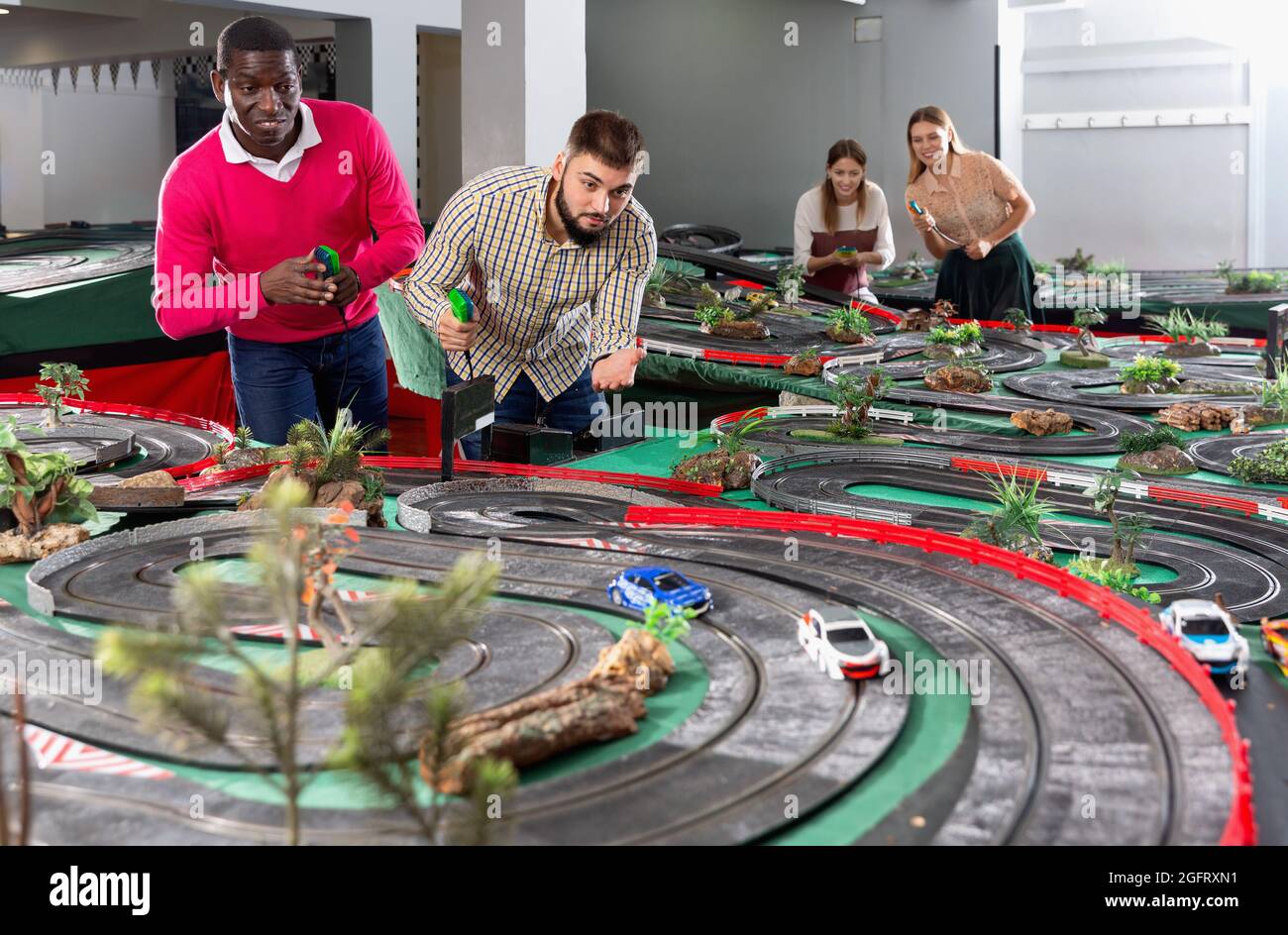 Two adult men playing with childrens slot car racing track Stock Photo ...