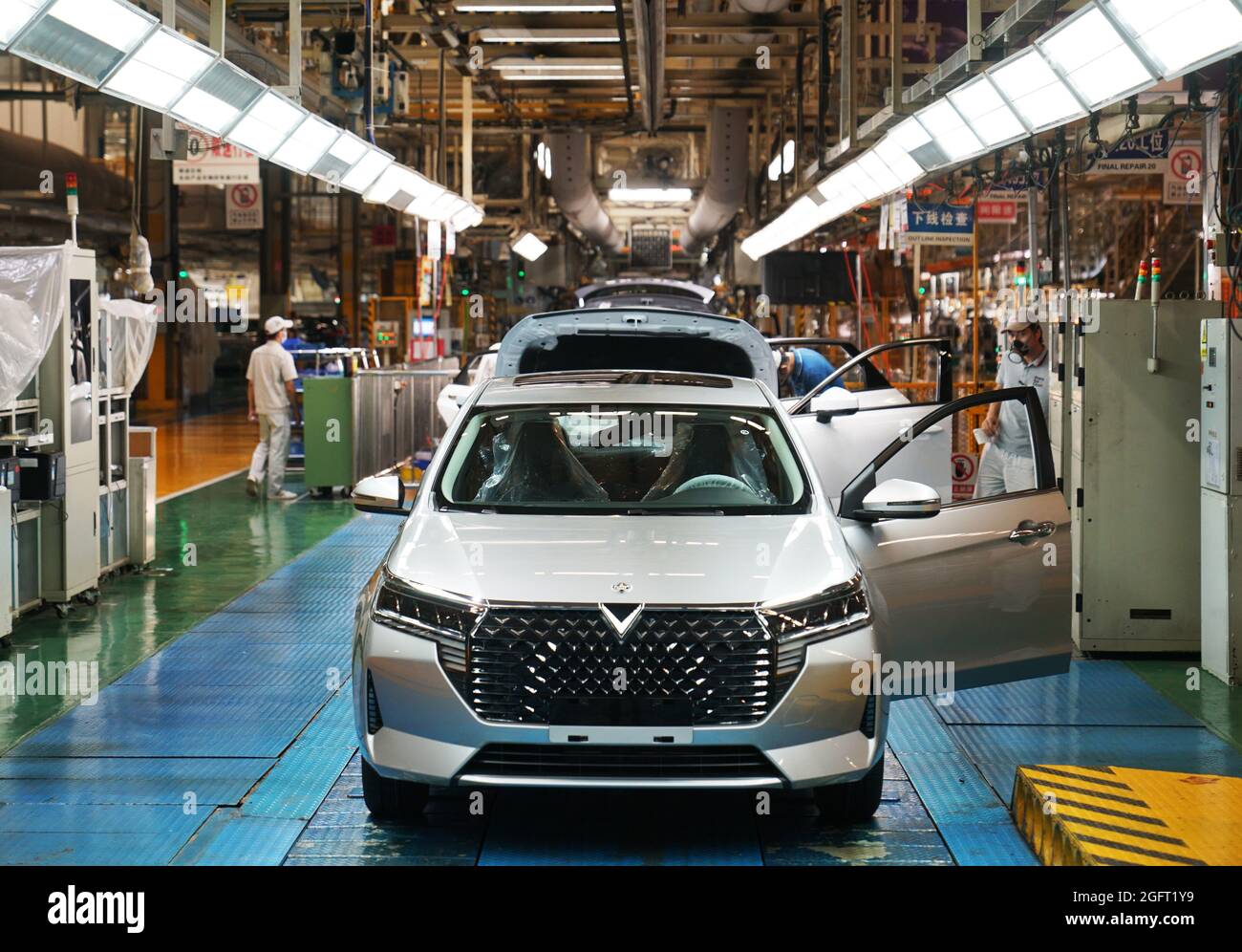 Workers assemble parts and vehicles at a factory of Dongfeng Nissan ...