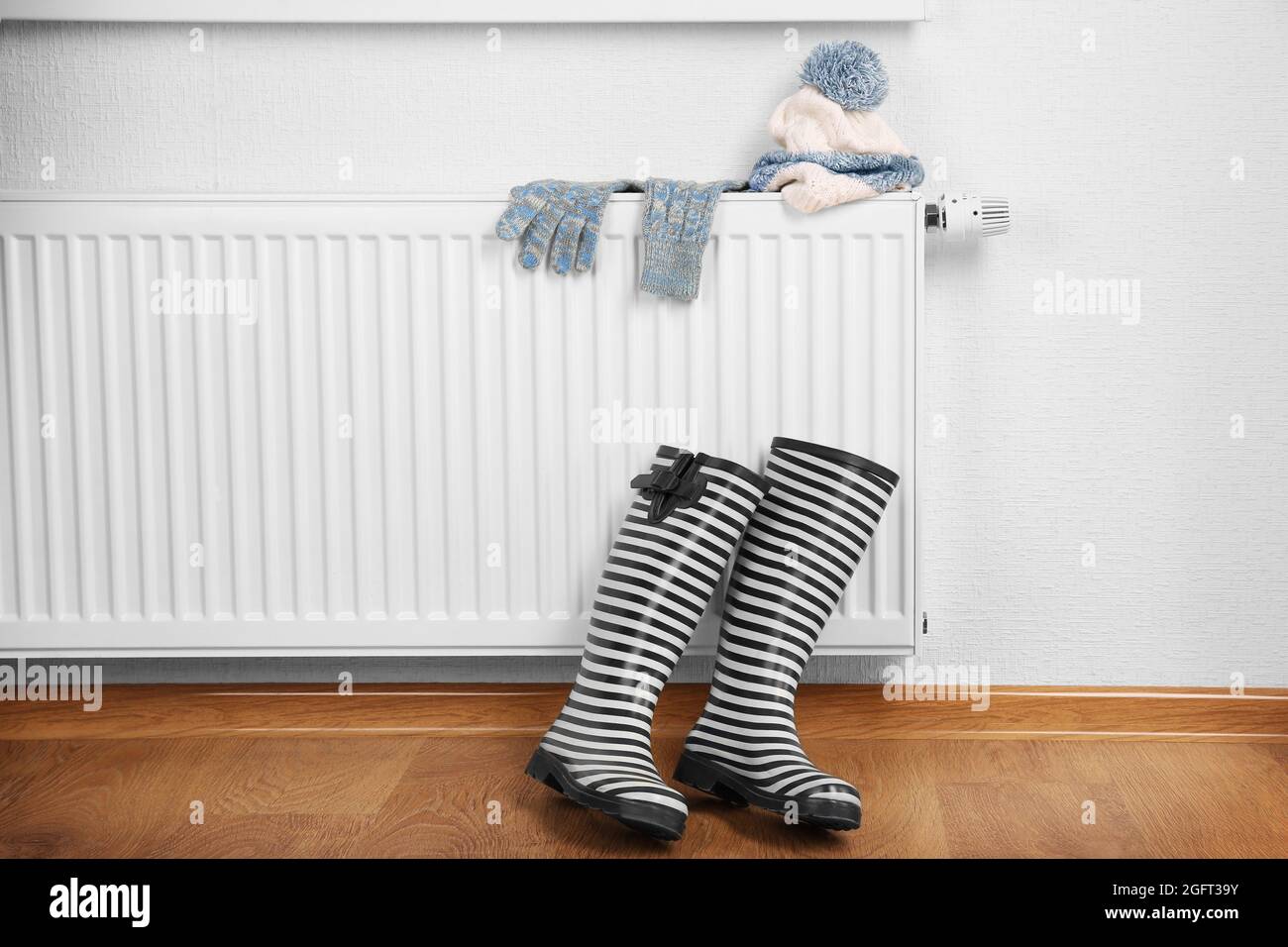 Heating radiator with rubber boots and warm clothes indoor Stock Photo ...