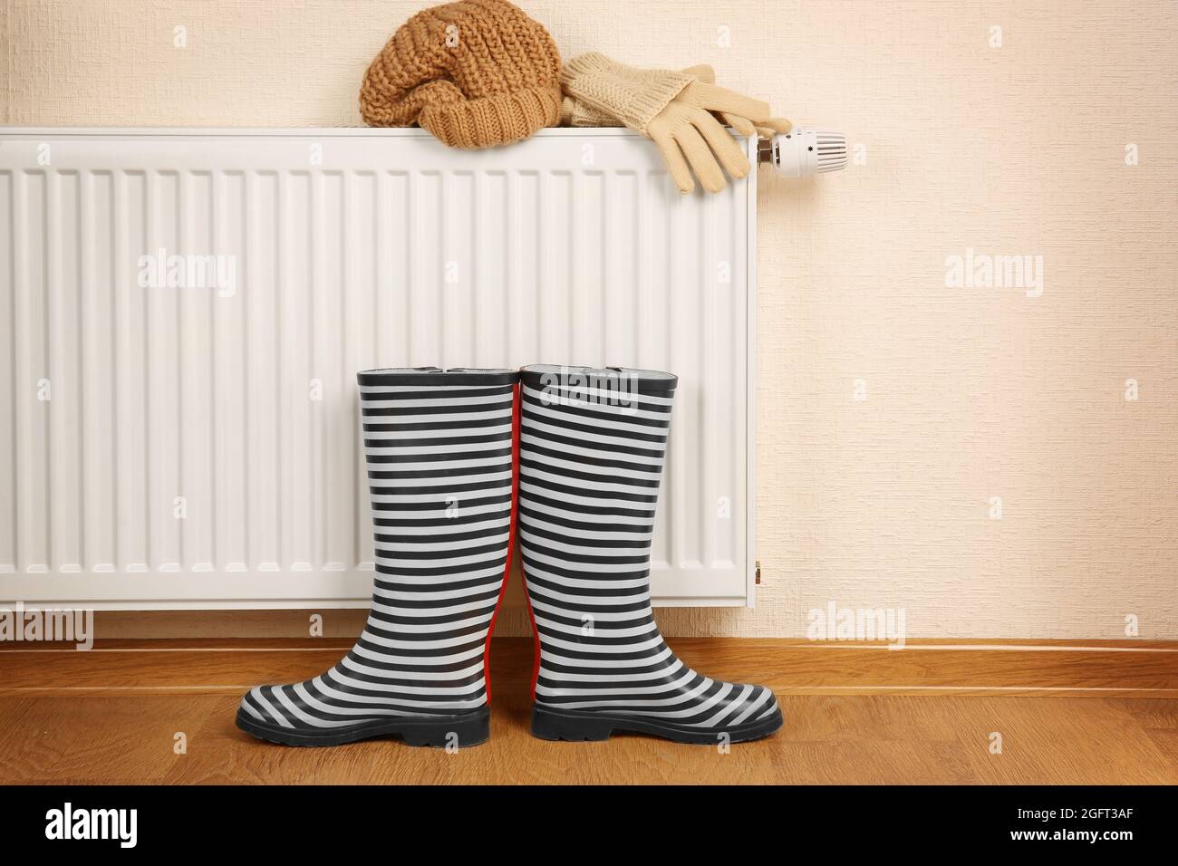 Heating radiator with rubber boots and warm clothes indoor Stock Photo ...