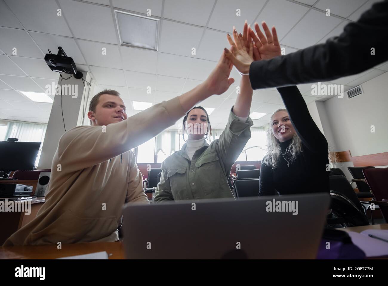 Students and lecturer give a high five in the university classroom ...