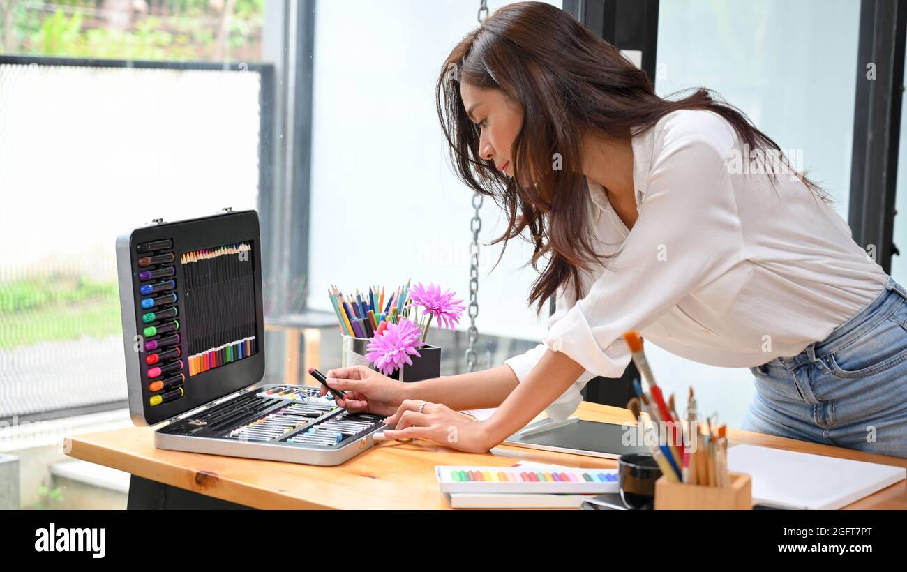Image of Attractive female graphic designer leaning on table, choosing ...