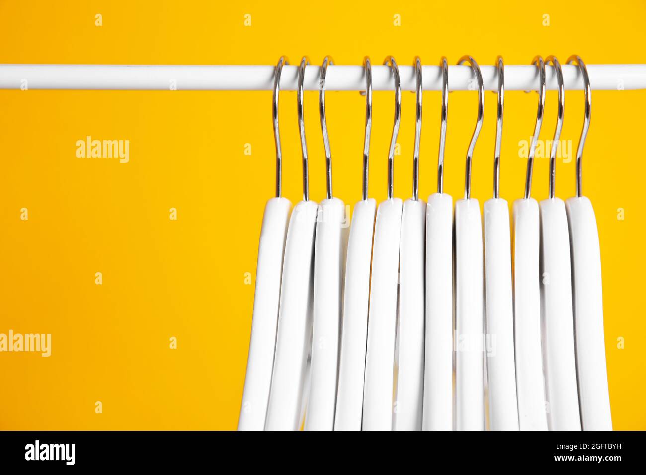 Modern hangers on yellow wall background Stock Photo - Alamy