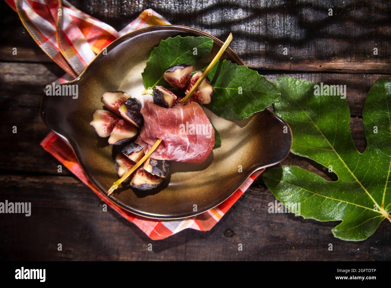 Presentation on plate skewer with figs and ham Stock Photo - Alamy
