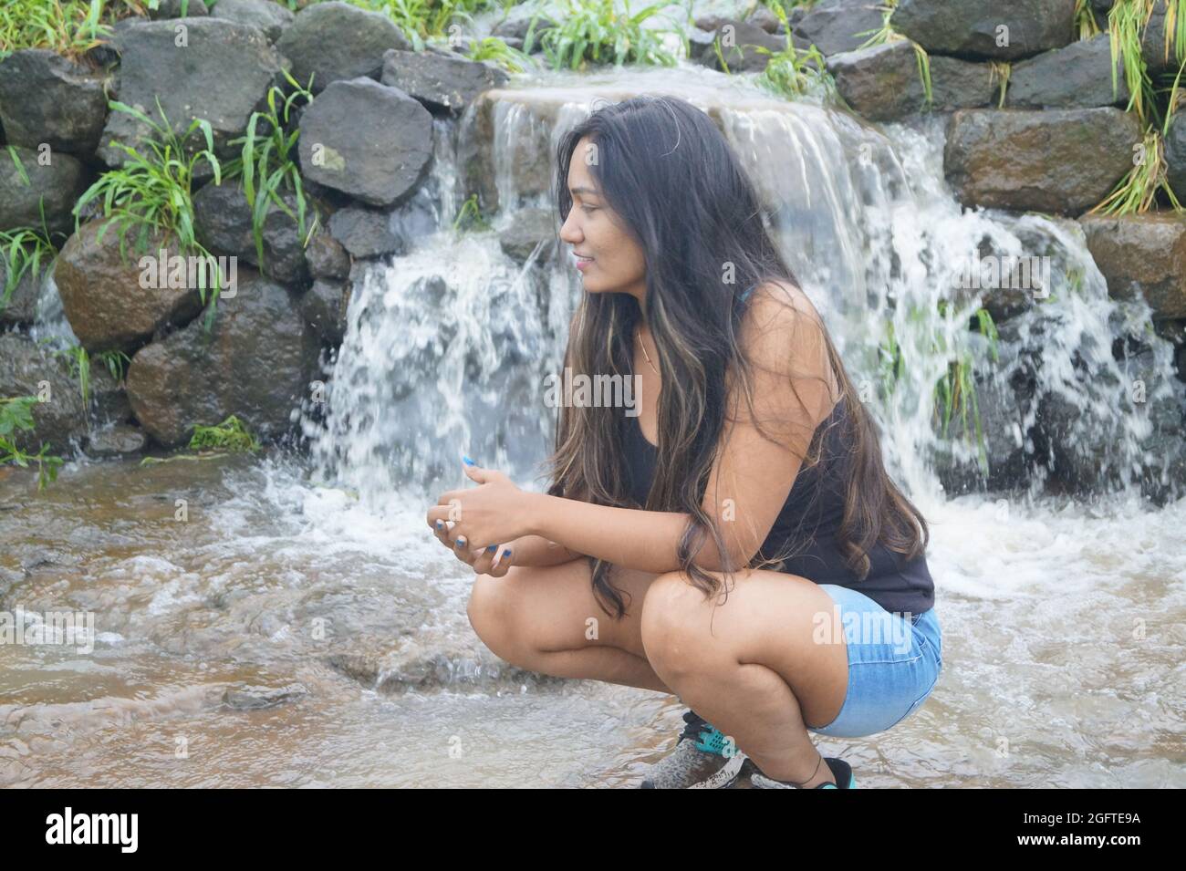 Gorgeous young South Asian lady from India crouching near a small ...