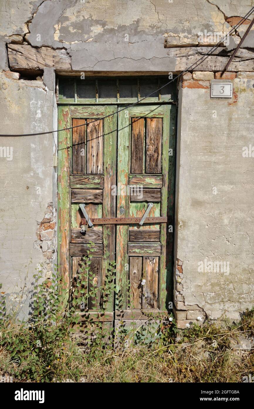 Entrance of an abandoned house with a closed damaged wooden door ...