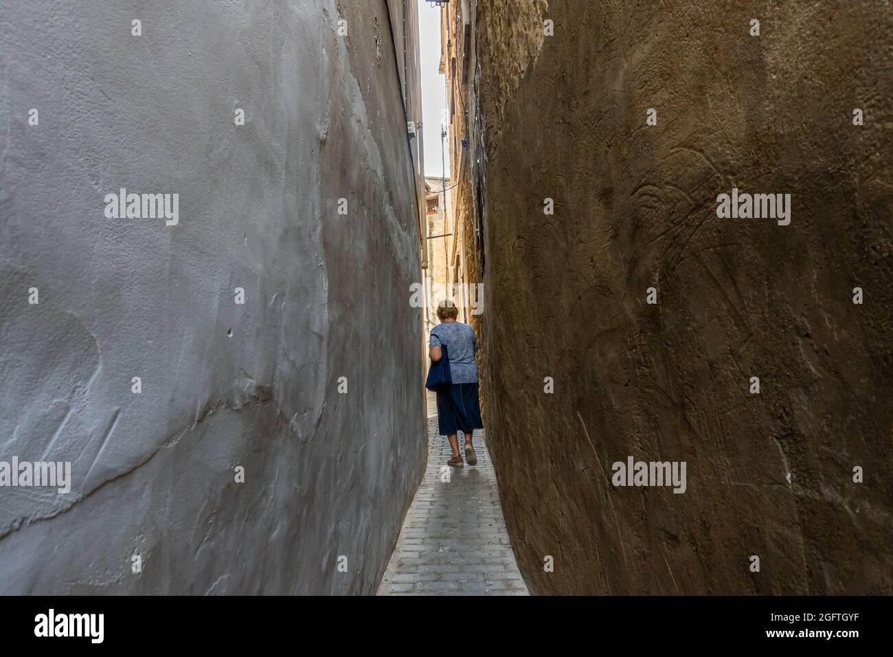 Rear shot of an elderly woman walking down a very narrow street Stock ...