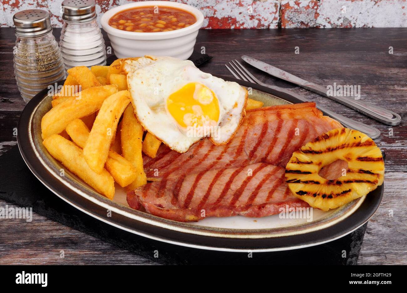 Grilled gammon egg and chips meal with baked beans and pineapple fruit ...
