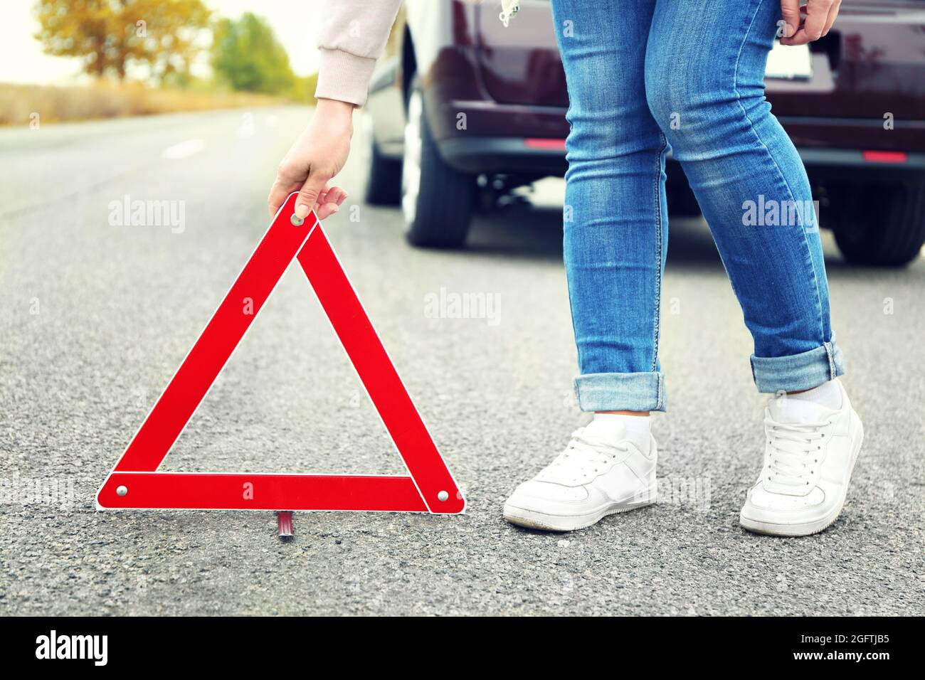 Female driver putting out traffic warning sign on road Stock Photo - Alamy