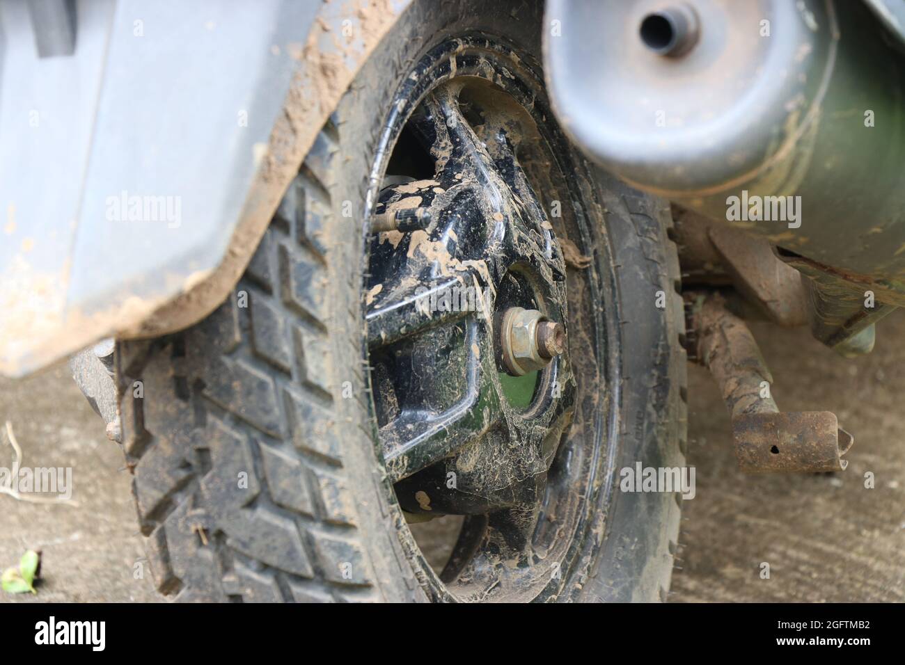 Scooter rear side wheel covered with mud after the ride. Tire closeup ...