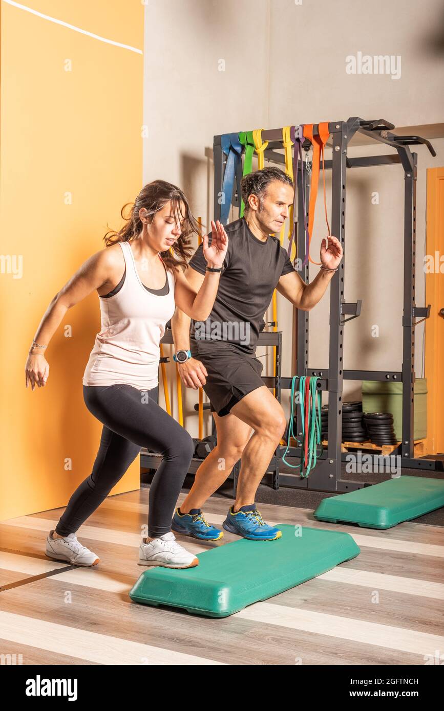 Athlete woman and man doing step up jumps in health club Stock Photo ...
