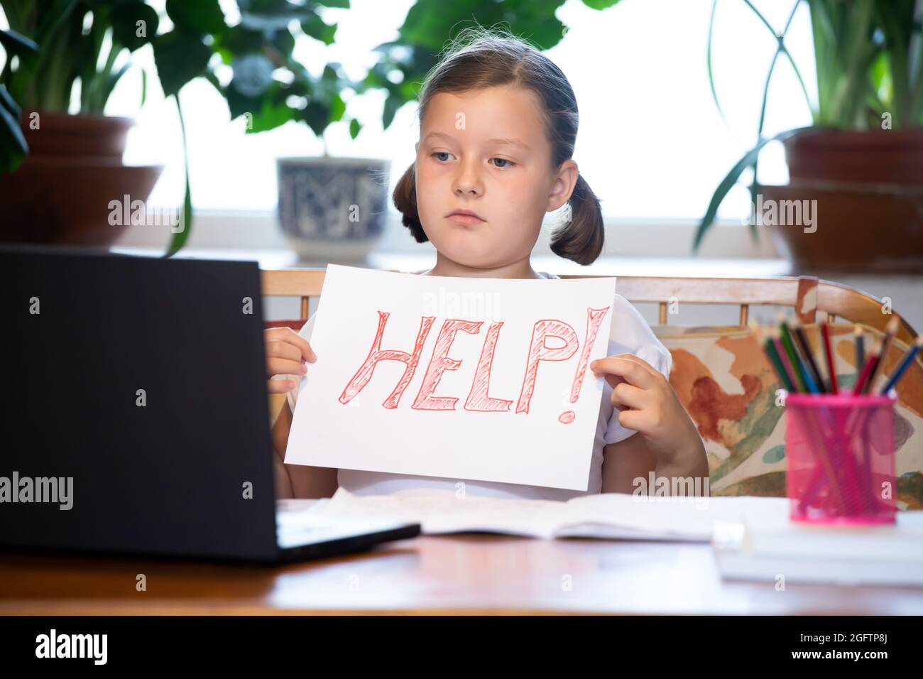 Distance learning concept. School girl holding help text during online ...