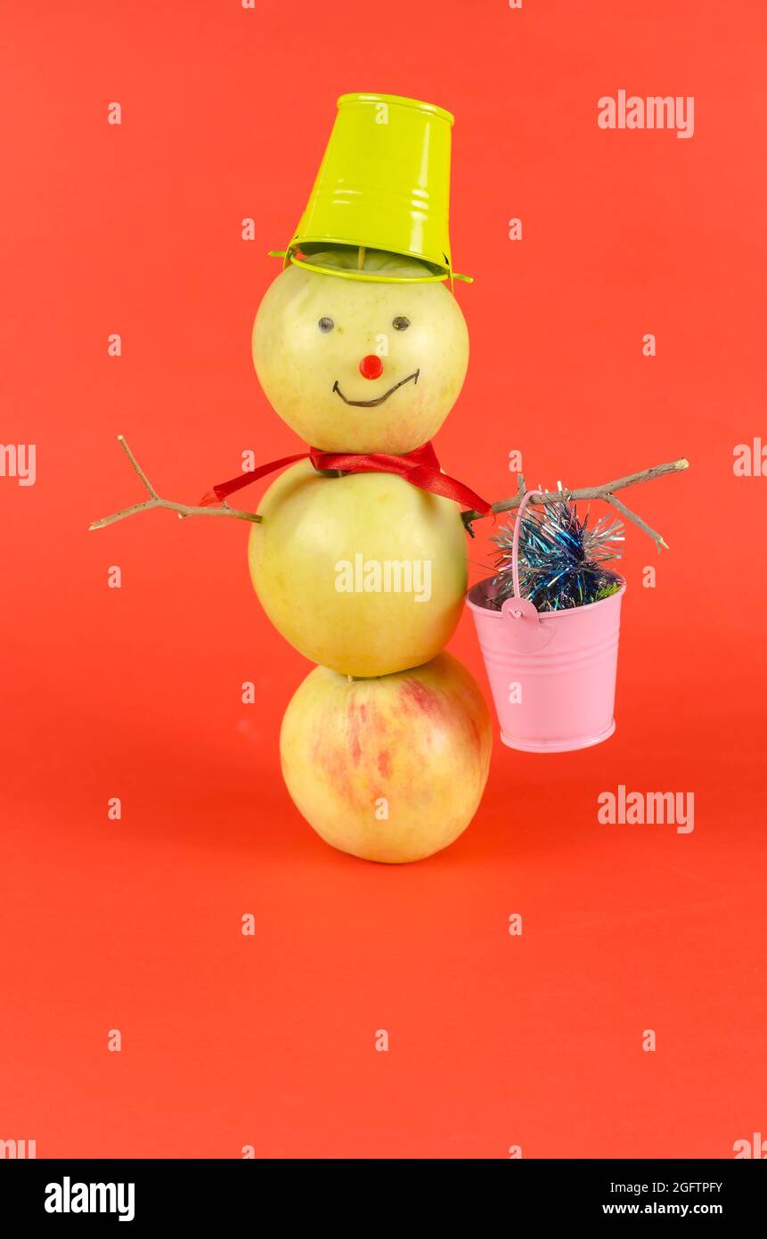 Apple snowman with a green bucket on his head standing on a red ...