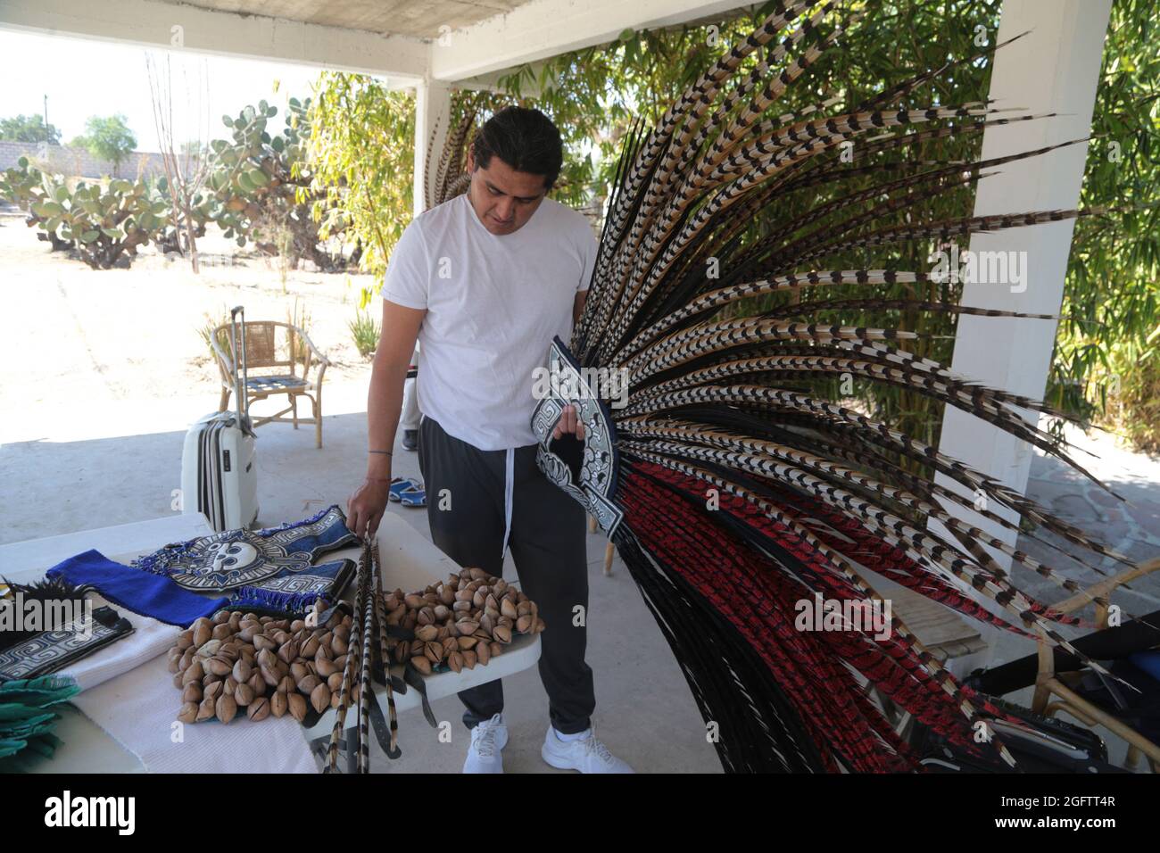 A man puts the feathers to a plume before dressed as aztec warrior as ...
