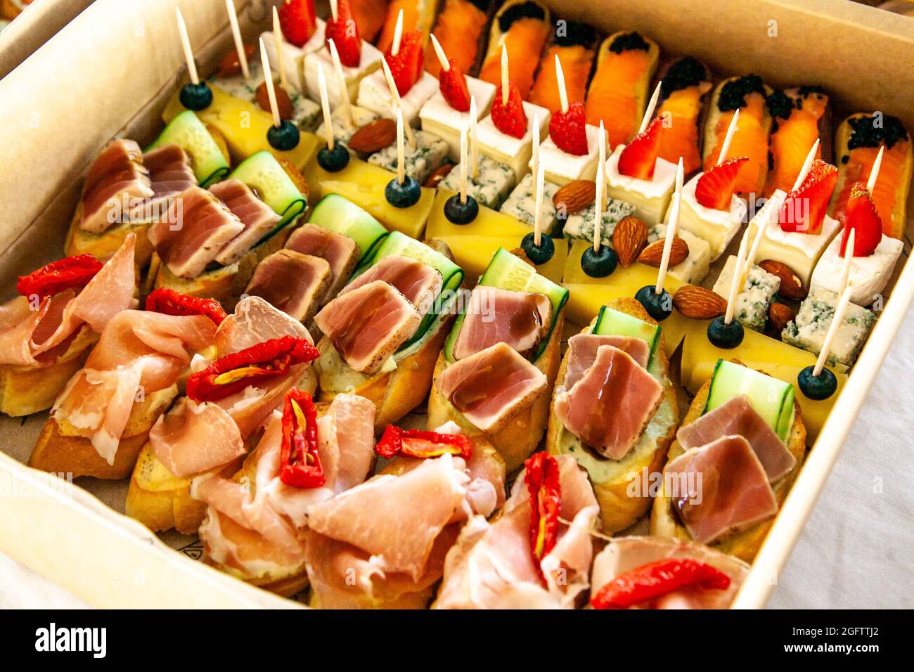 Box with small sandwiches, eclairs, bruschetta with cold cuts, cheese ...