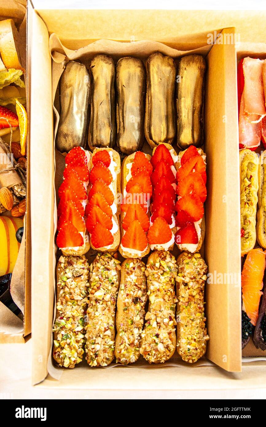 Gastronomic box with sweet eclairs with cheese mousse and fresh berries ...